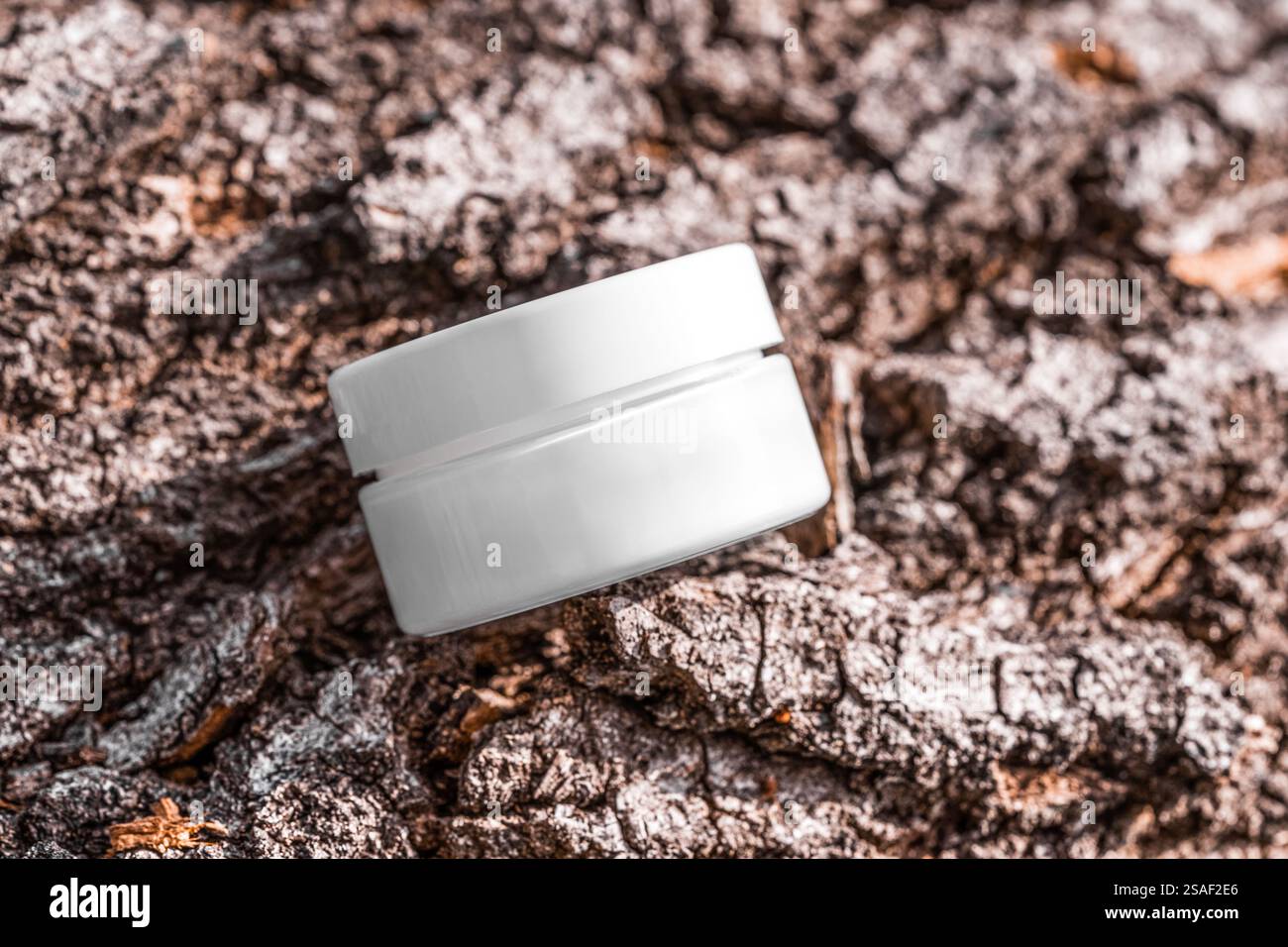 White cosmetic jar of firming cream on rugged tree bark surface display ...