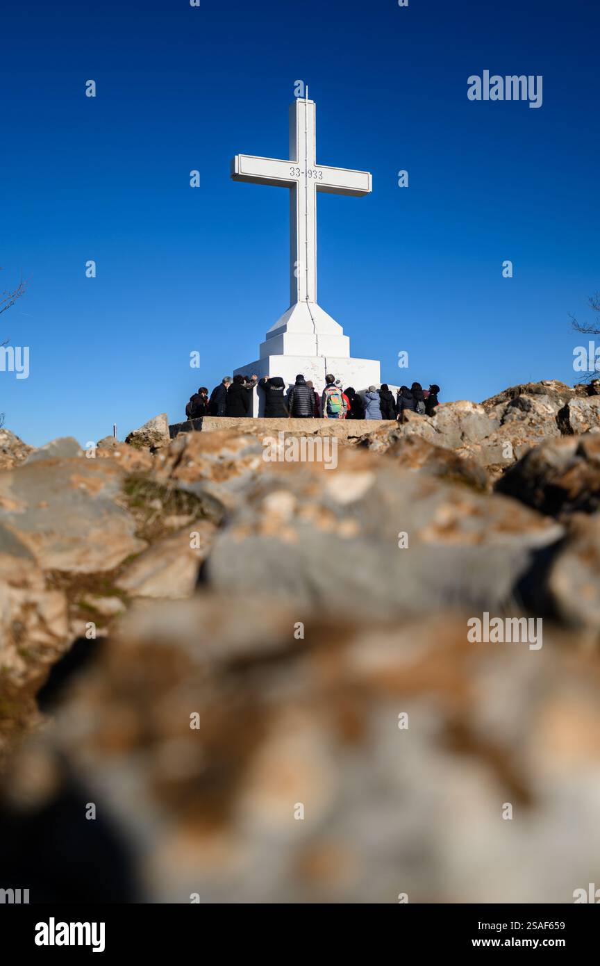 Pilgrims praying around the white cross on the top of Mount Križevac ...