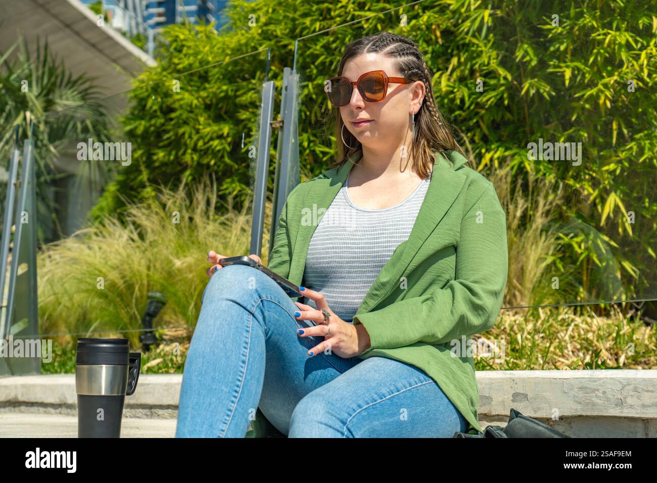 A relaxed woman enjoys an outdoor break, holding a coffee cup and ...