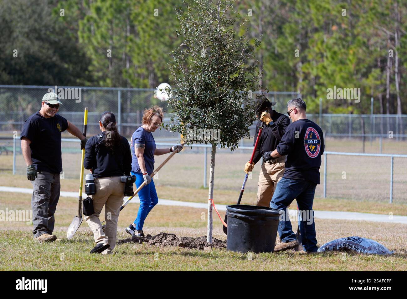 Volunteers plant trees at Eagles Nest Park community center during a ...