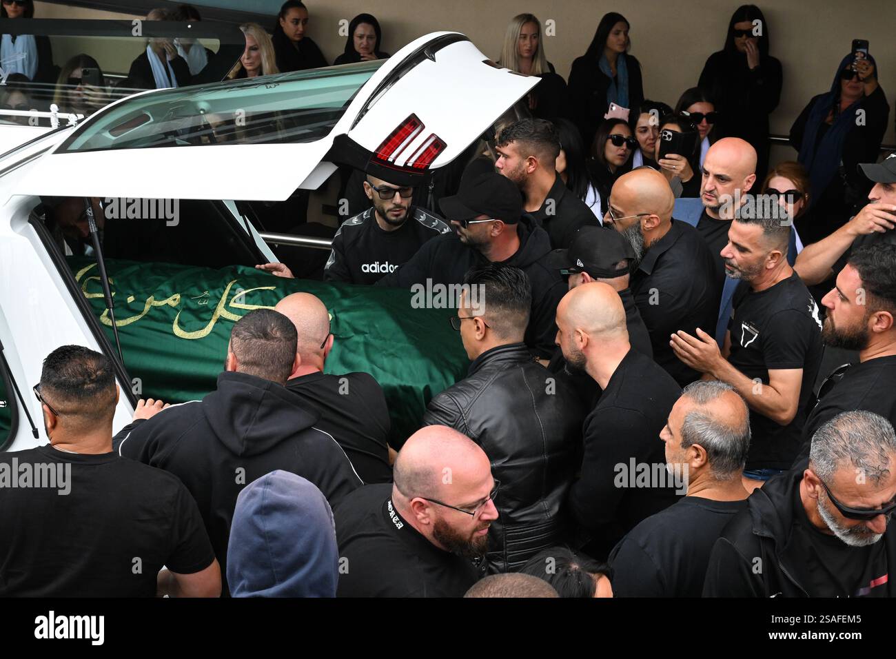 Pallbearers carry the casket to a hearse following the service for ...