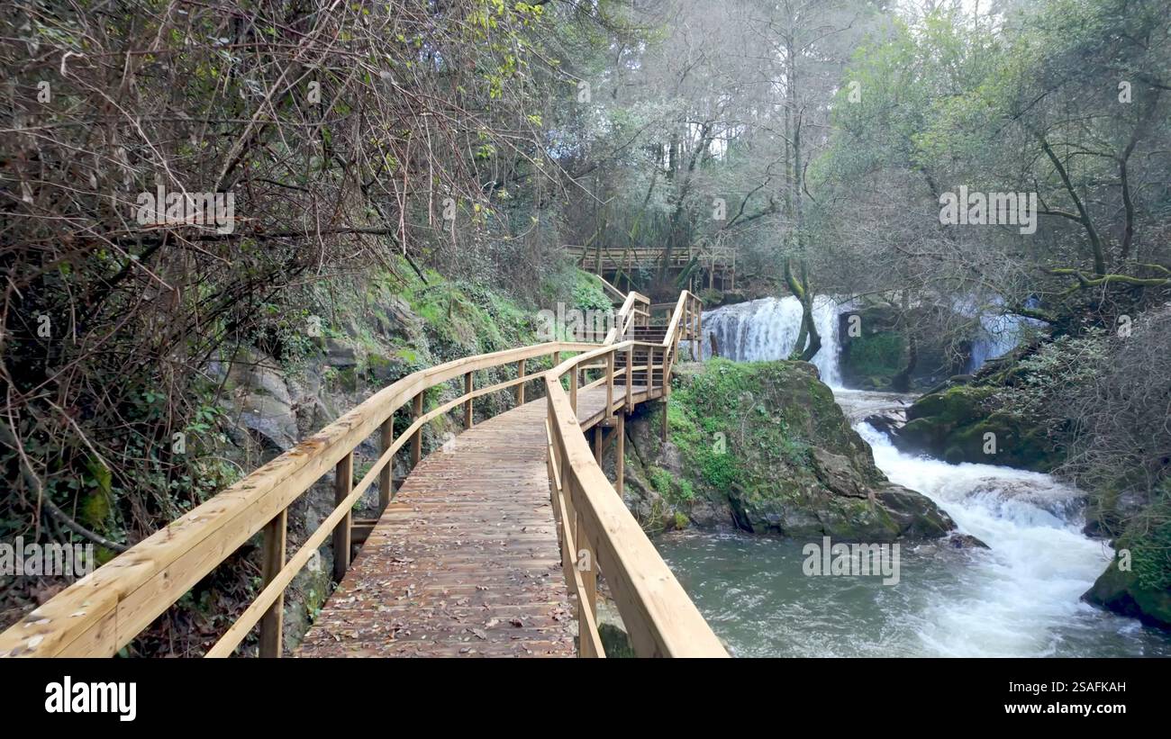 A wooden walkway leads to a cascading waterfall at Cascata do Outeiro ...