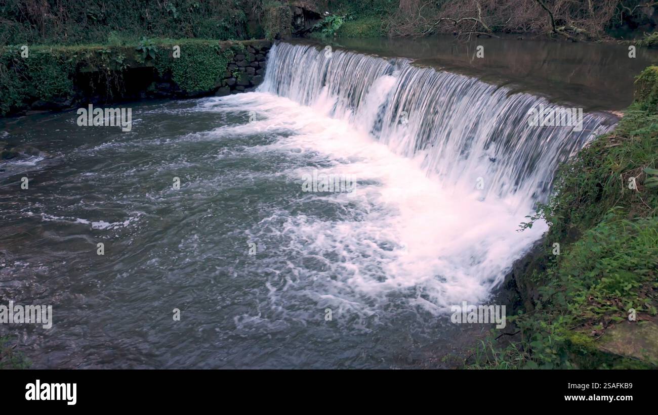 A powerful flow of water cascades over a man-made weir near Cascata do ...