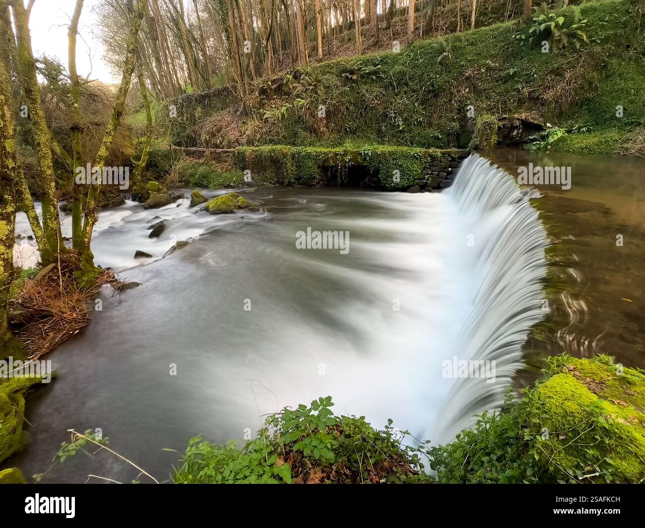 Water cascades over a stone weir, creating a mesmerizing scene near ...