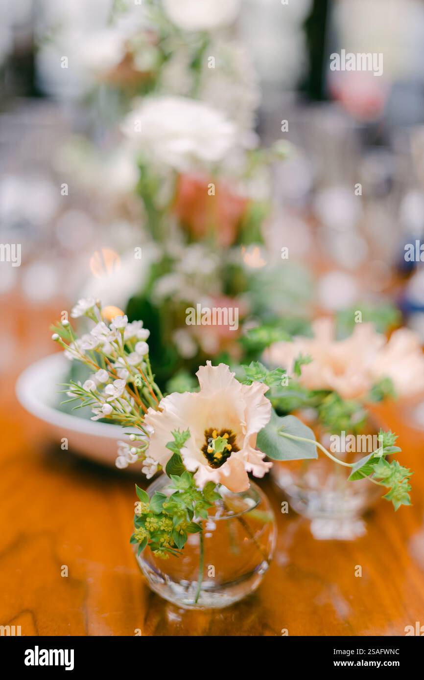 Elegant floral arrangements adorn a wooden table, featuring delicate ...