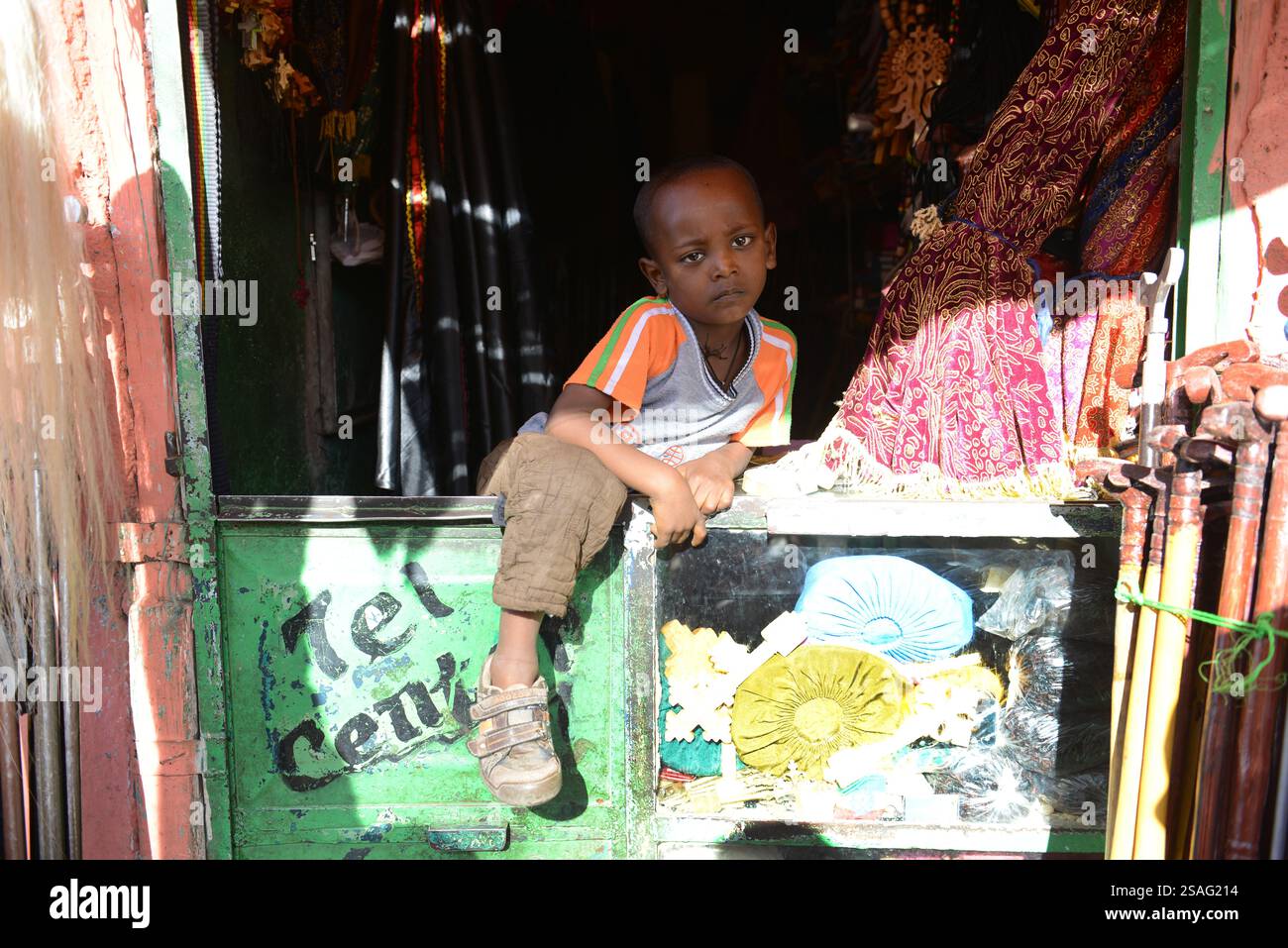 A cute boy sitting on the counter of a small shop in Gondar, Ethiopia ...