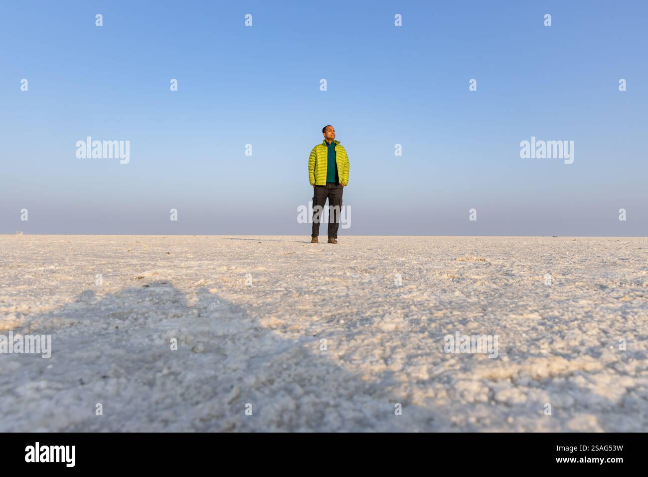 young man standing at white salt desert with bright blue sky at morning ...