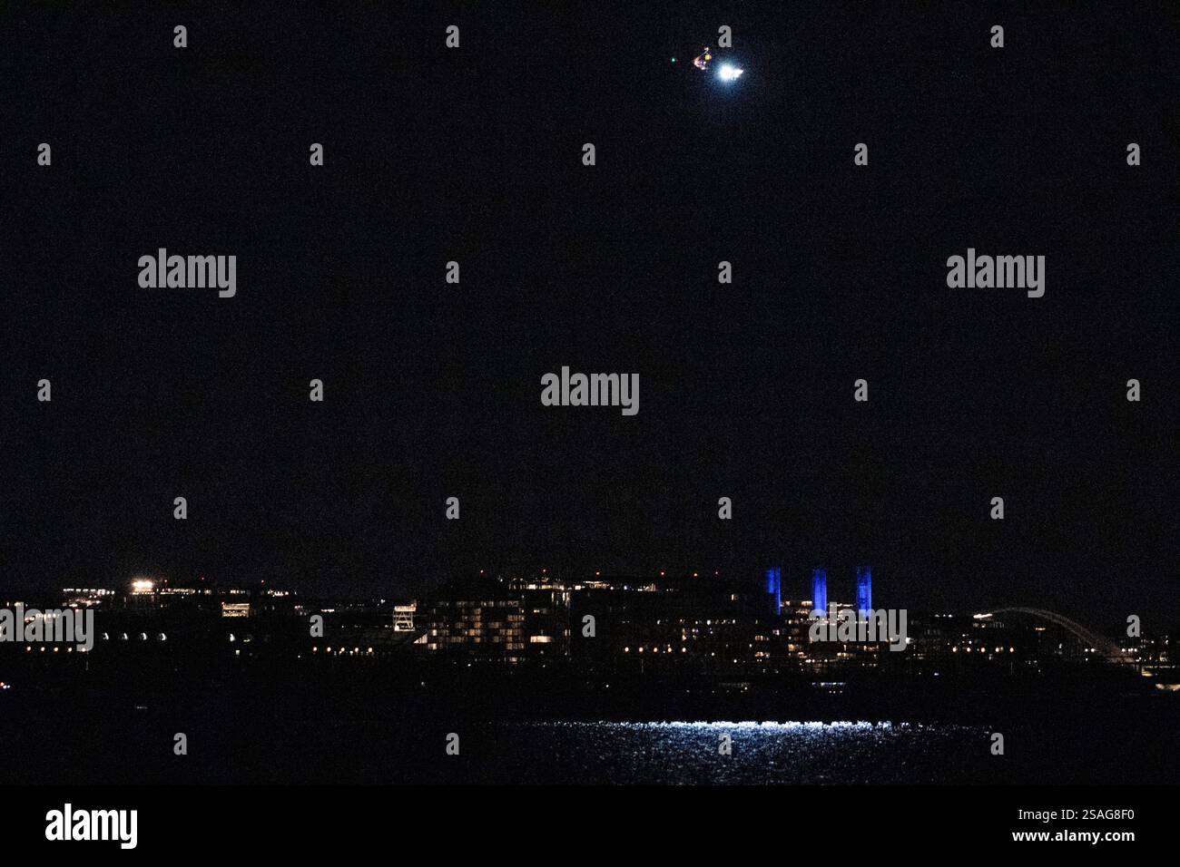 A helicopter uses its searchlight as it flies above the Potomac River ...