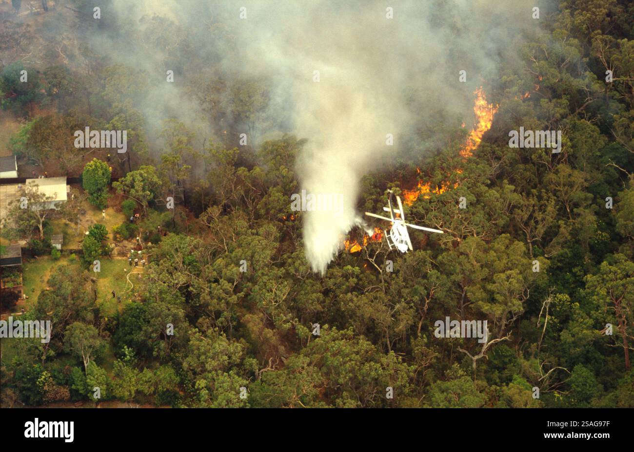 Aerial view of water dropping from helicopter onto a bushfire near ...