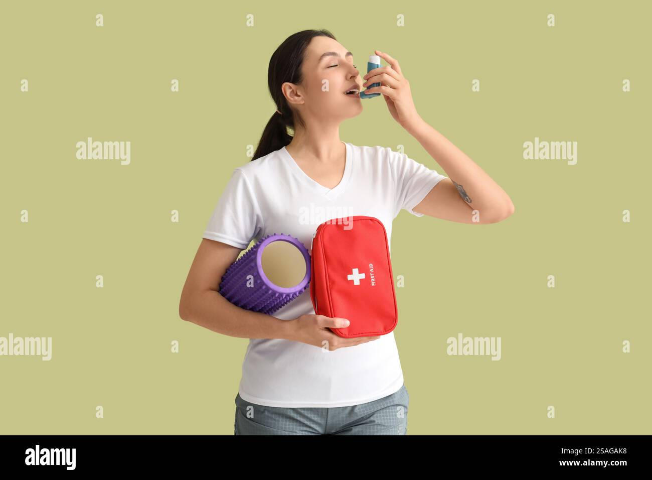 Sporty young woman with first aid kit and foam roller using inhaler on ...
