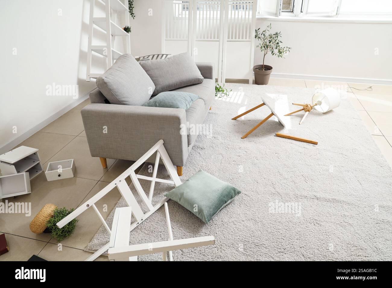 Sofa with broken table and chair in messy living room Stock Photo - Alamy