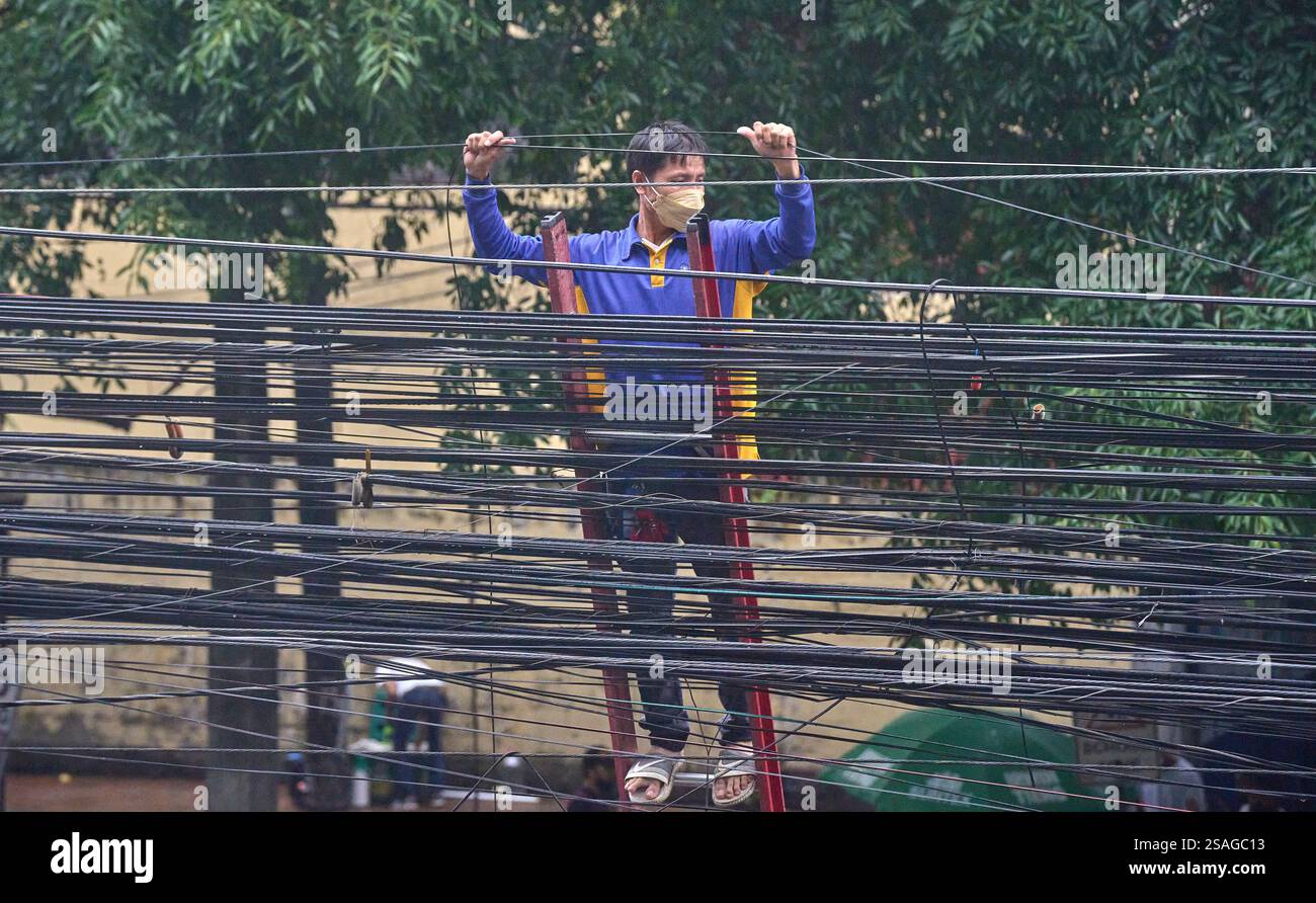 Leaning his ladder against a plethora of wires, a worker sorts out ...