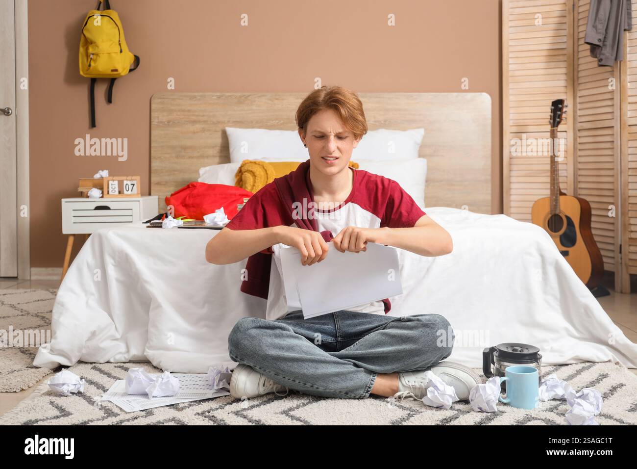 Stressed male student tearing papers in bedroom Stock Photo - Alamy