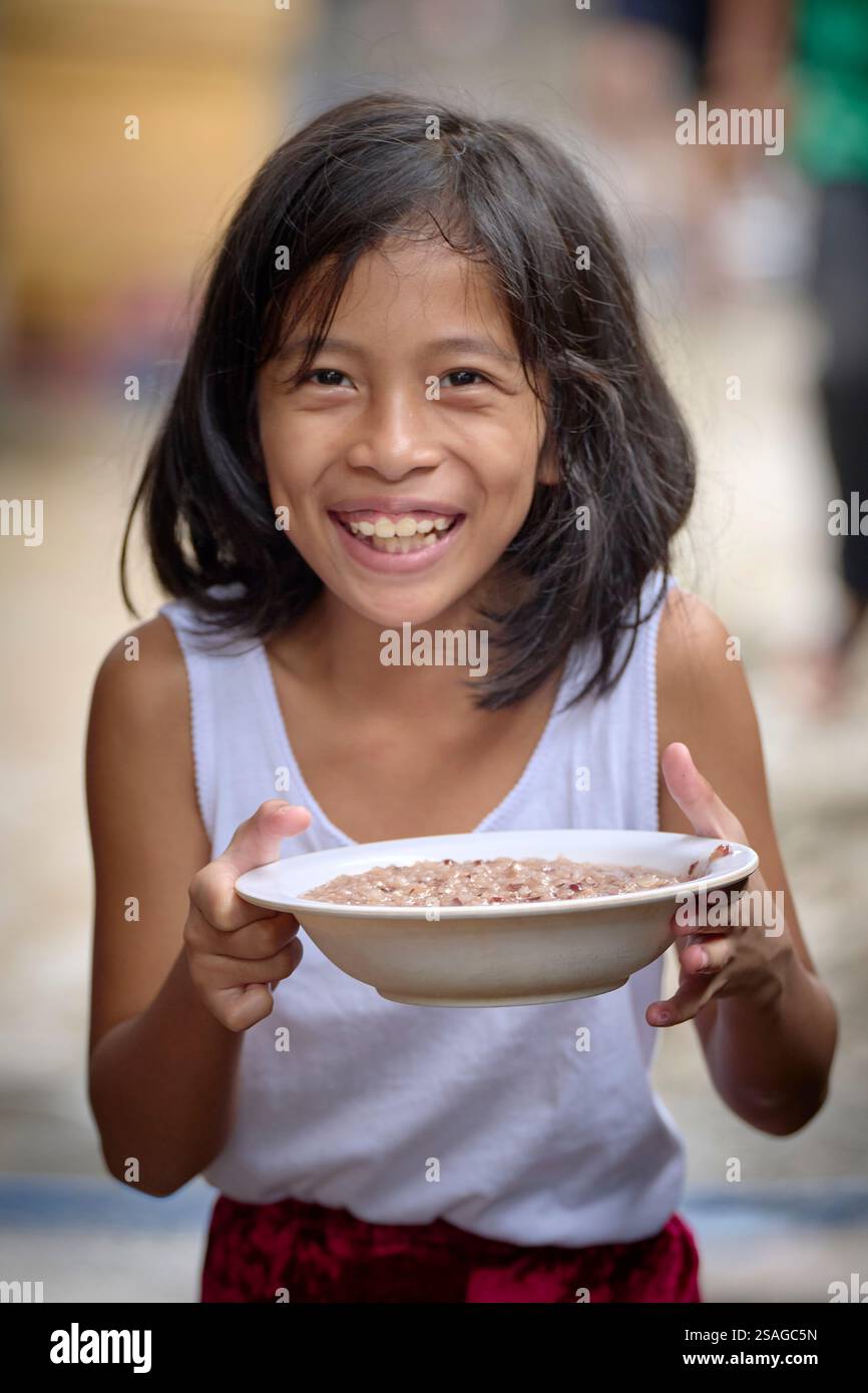A girl carries home a plate of rice and beans from a feeding program ...