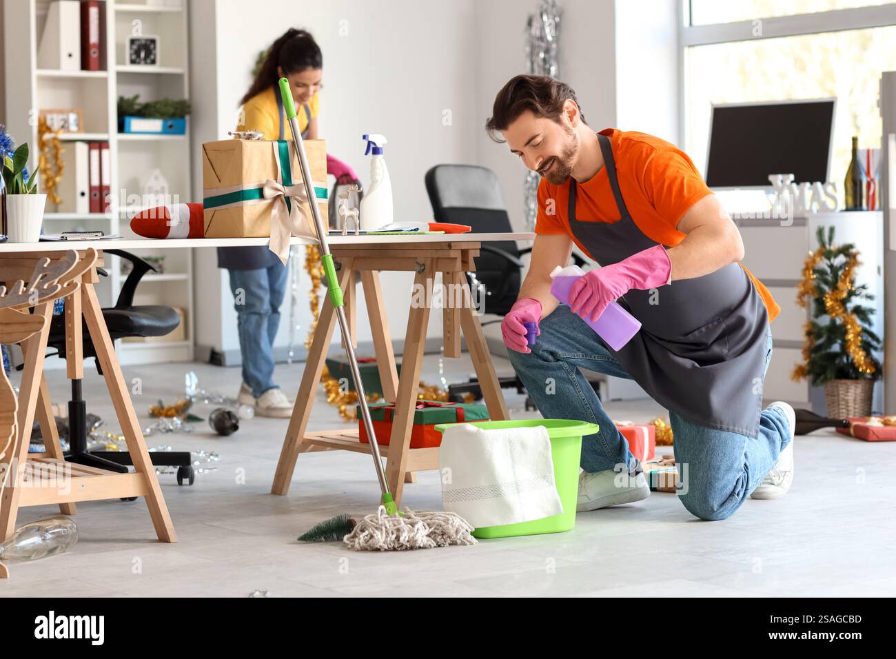 Male janitor pouring detergent into bucket in office after New Year ...