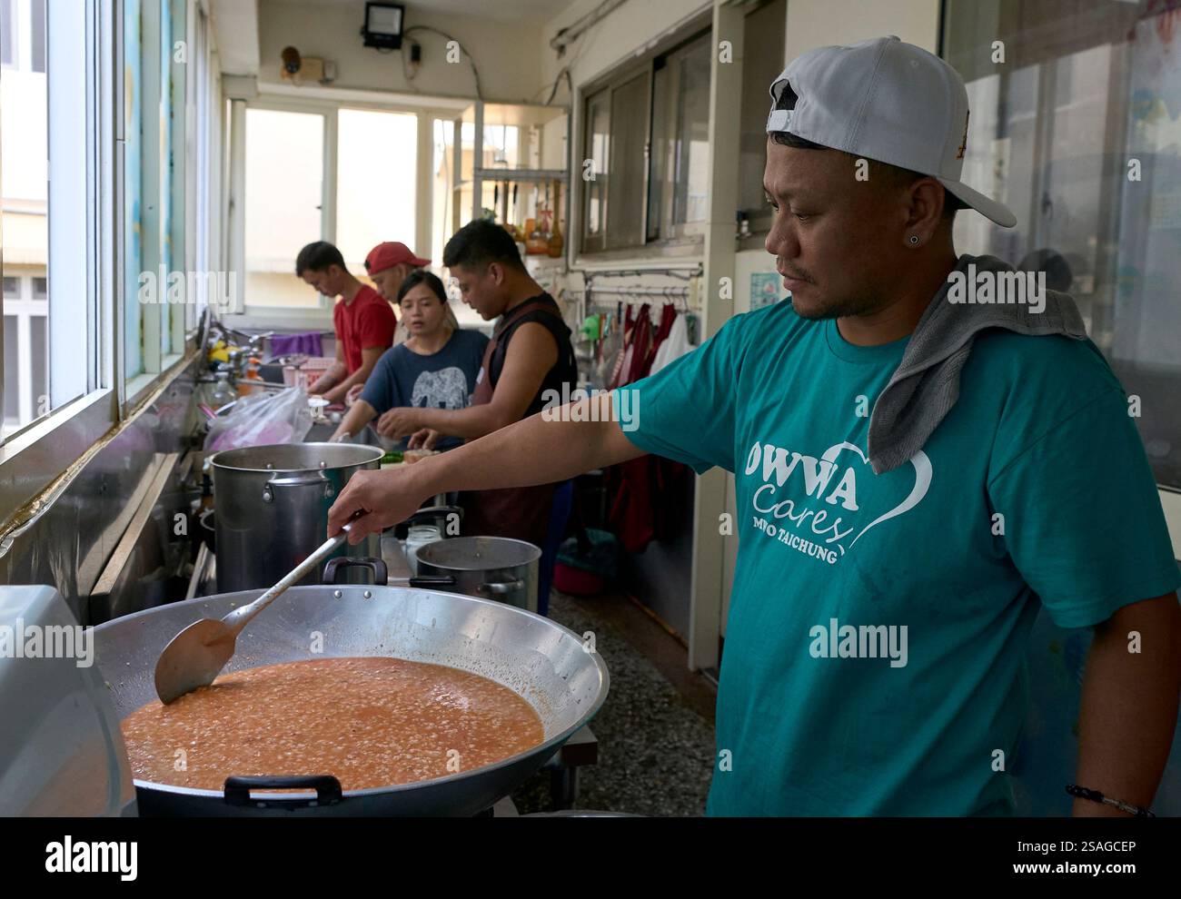 Charlie Cabasa (right) and other residents prepare a meal in the ...