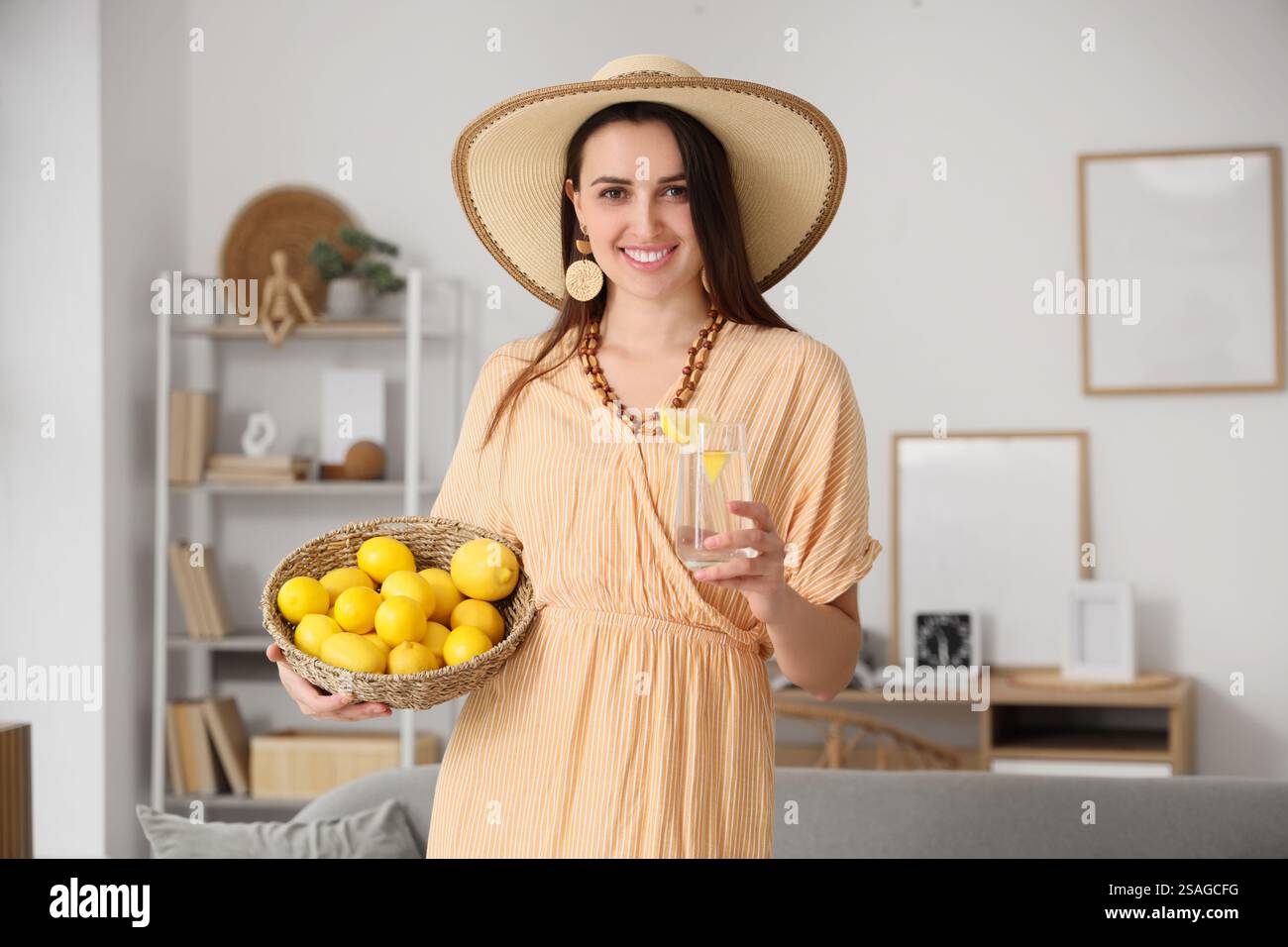 Beautiful young woman with fresh lemons and glass of infused water at ...