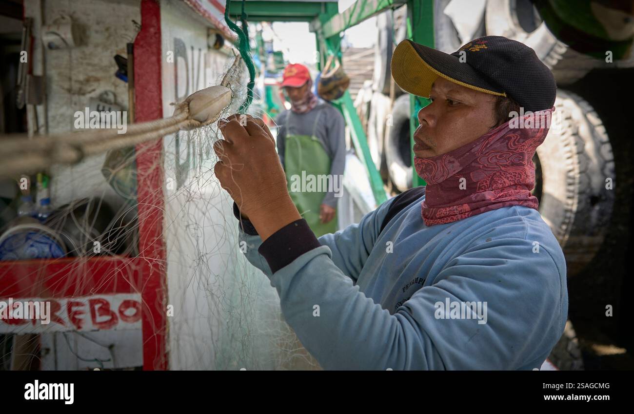 Migrant workers repair nets on a fishing boat in Taichung Harbor, the ...