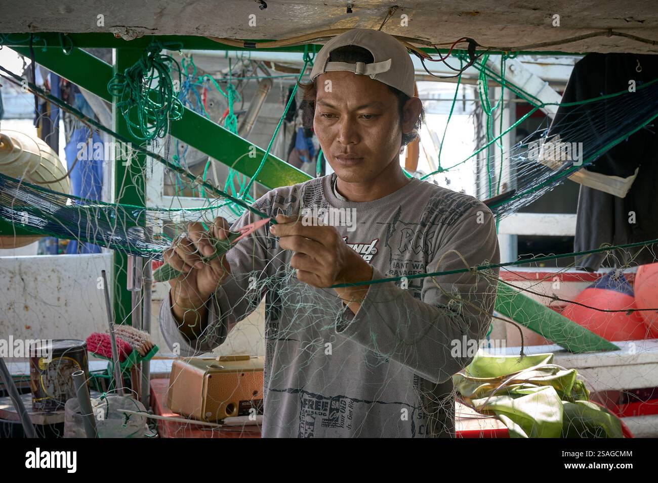 Migrant workers repair nets on a fishing boat in Taichung Harbor, the ...