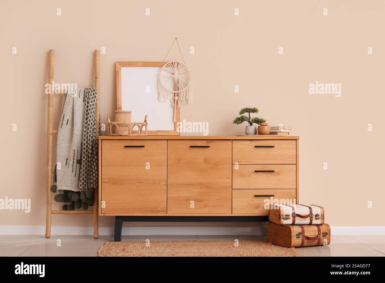 Interior of modern room with stylish dresser and ladder near beige wall ...