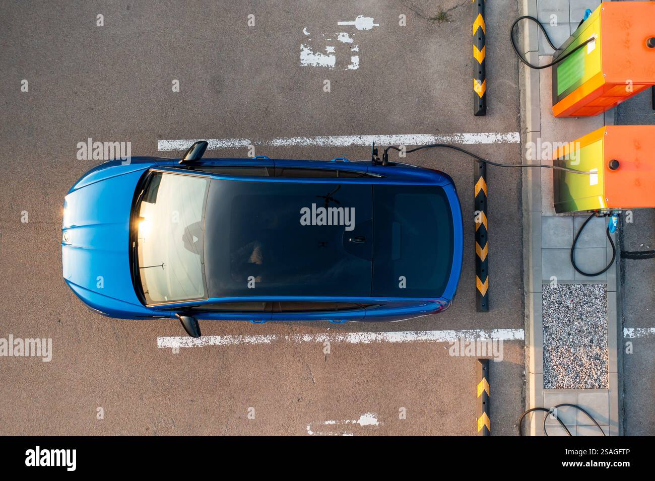 Blue cars receive electricity at a charging station, top view. Modern ...