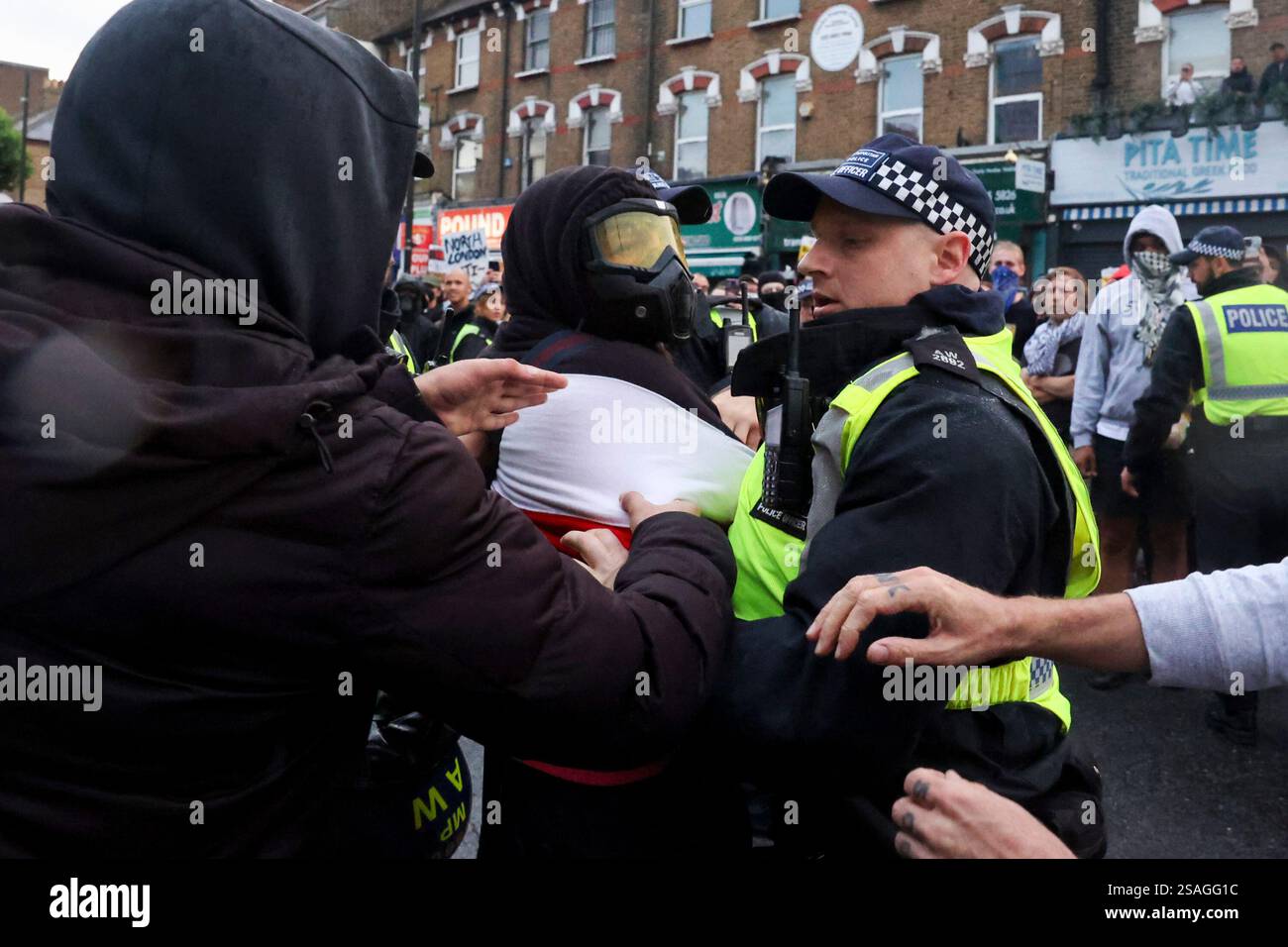 Police remove a protestor as crowds gather in North Finchley, London ...