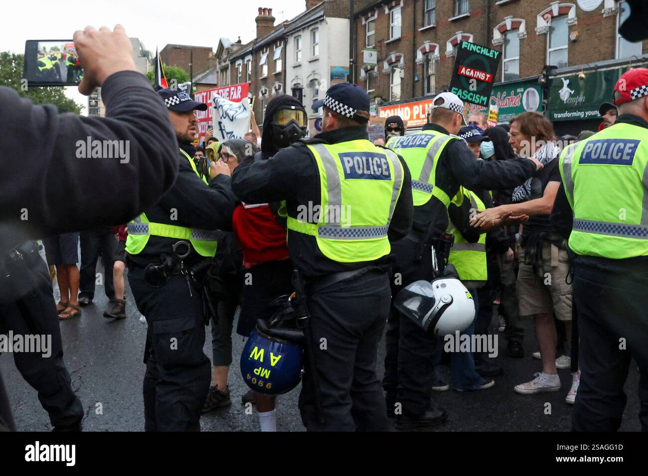 Police remove a protestor as crowds gather in North Finchley, London ...