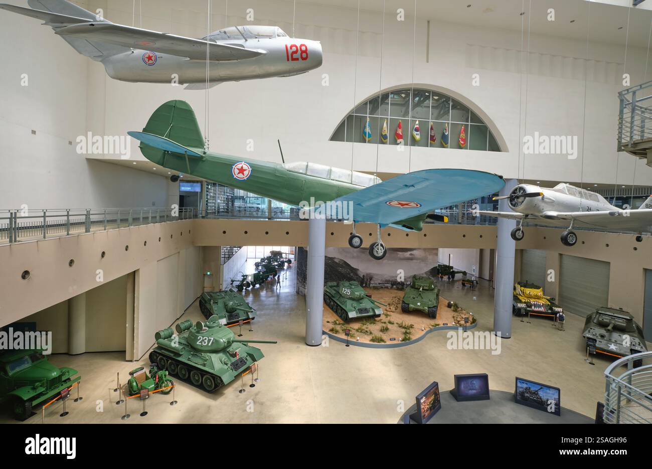 Overview of a large atrium with tanks, military equipment and airplanes ...