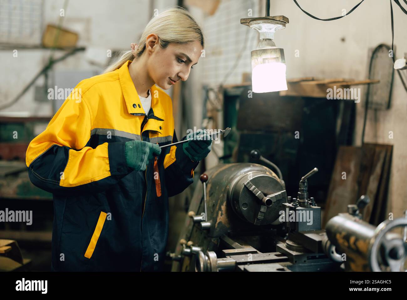 female worker using vernier caliper measuring metal part in lathe ...