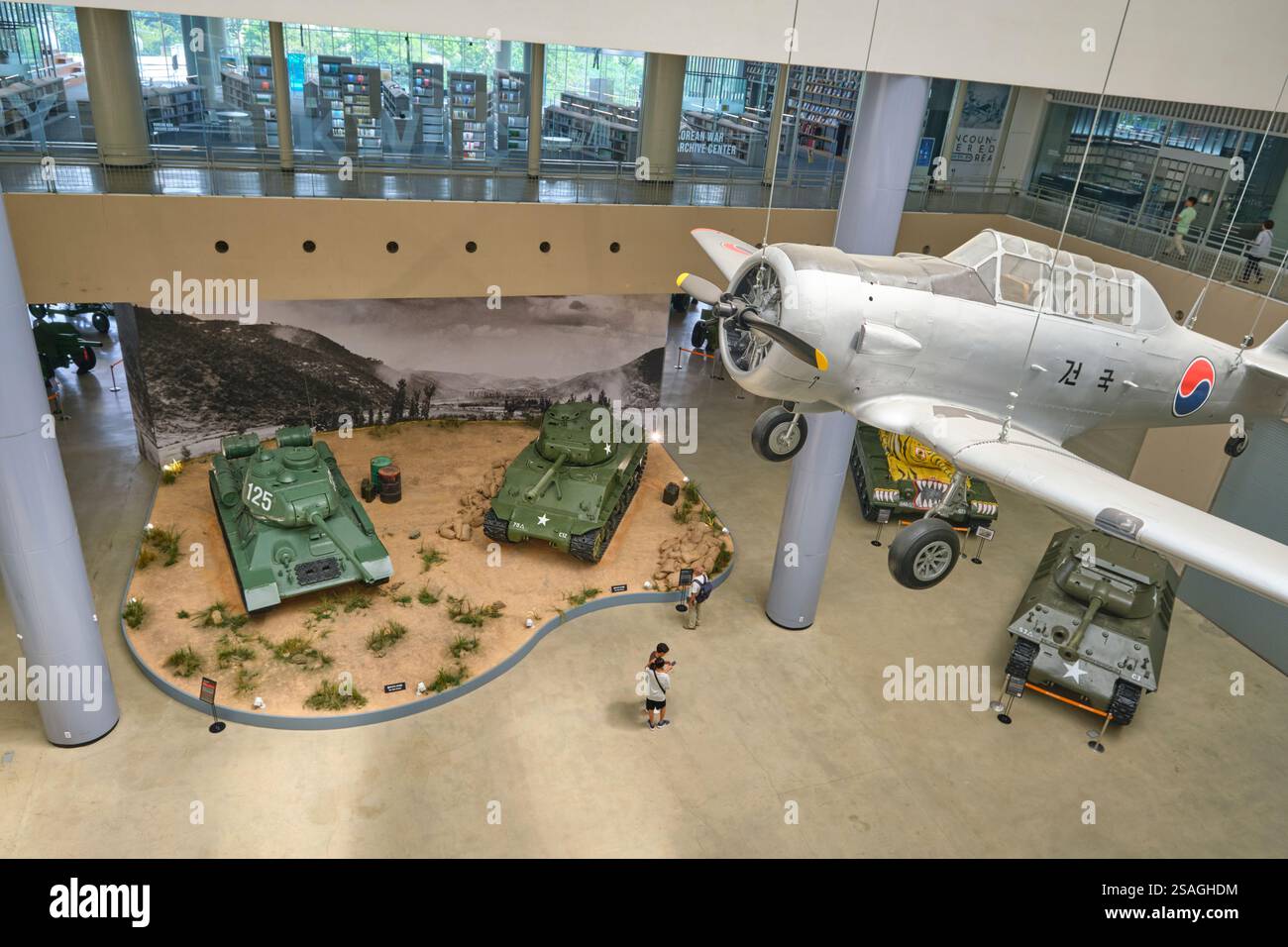 Overview of a large atrium with tanks, military equipment and airplanes ...