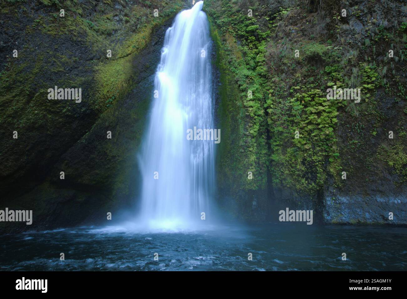 Massive waterfall with water streaming down between sheer rock faces ...