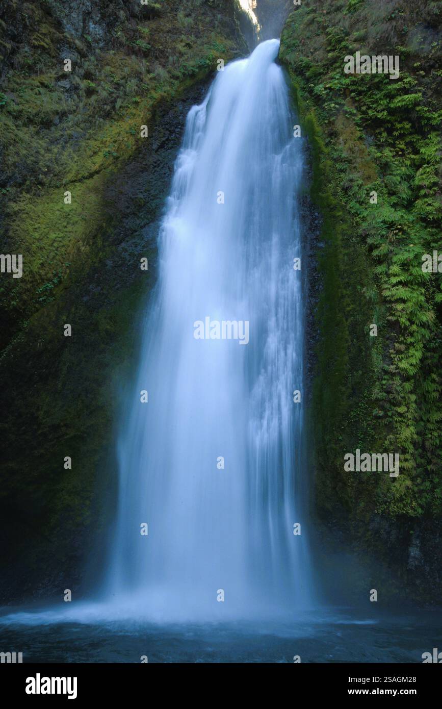 Massive waterfall with water streaming down between sheer rock faces ...