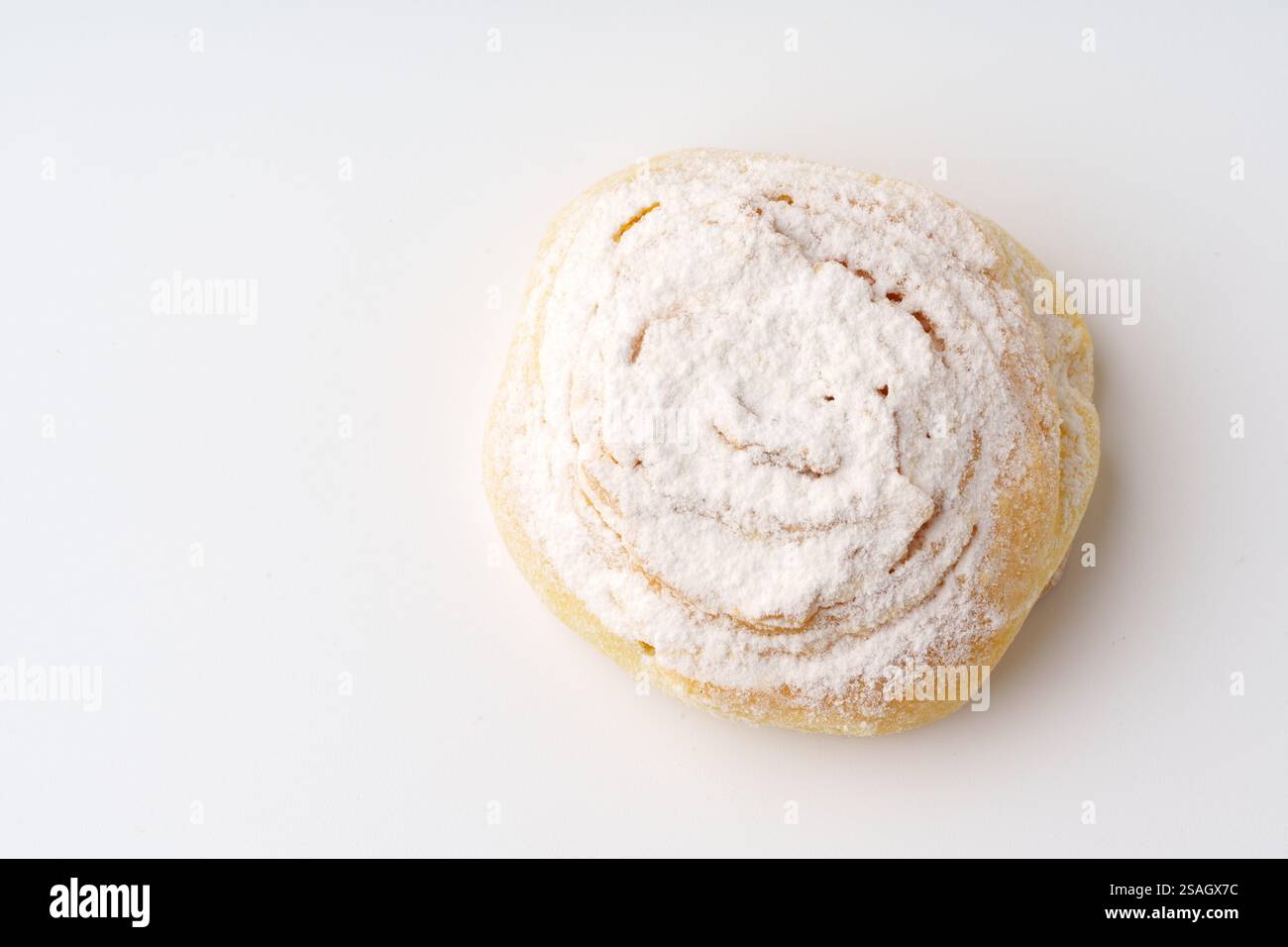 Freshly baked sweet roll topped with powdered sugar on a clean white ...