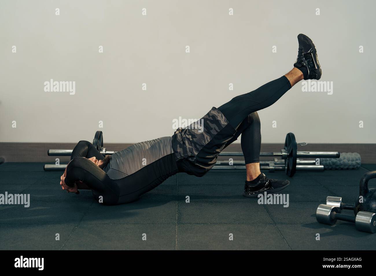 Fitness enthusiast performs leg raises on a gym mat during a workout ...