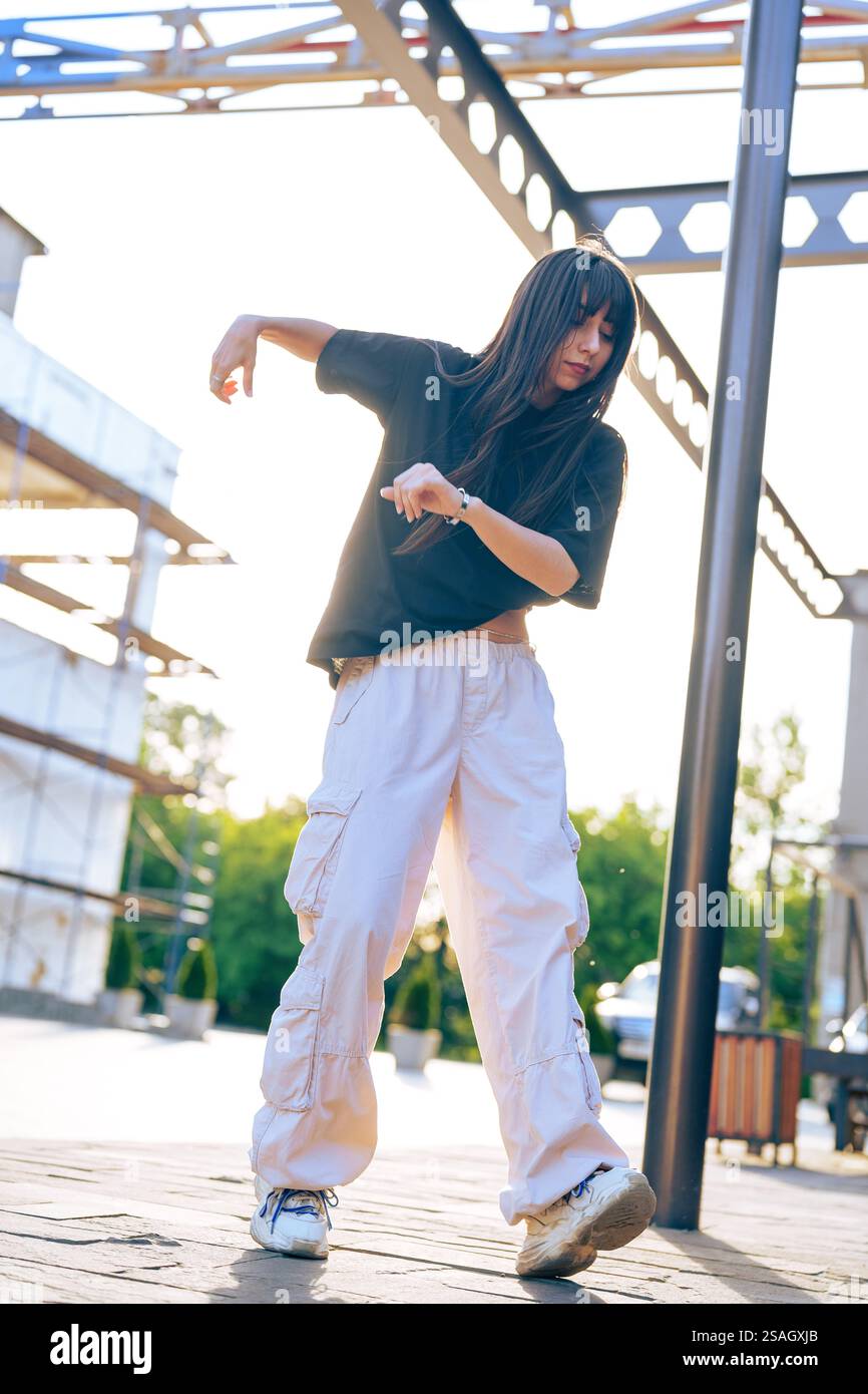 Dancer performs expressive movements in a stylish outfit during sunset ...