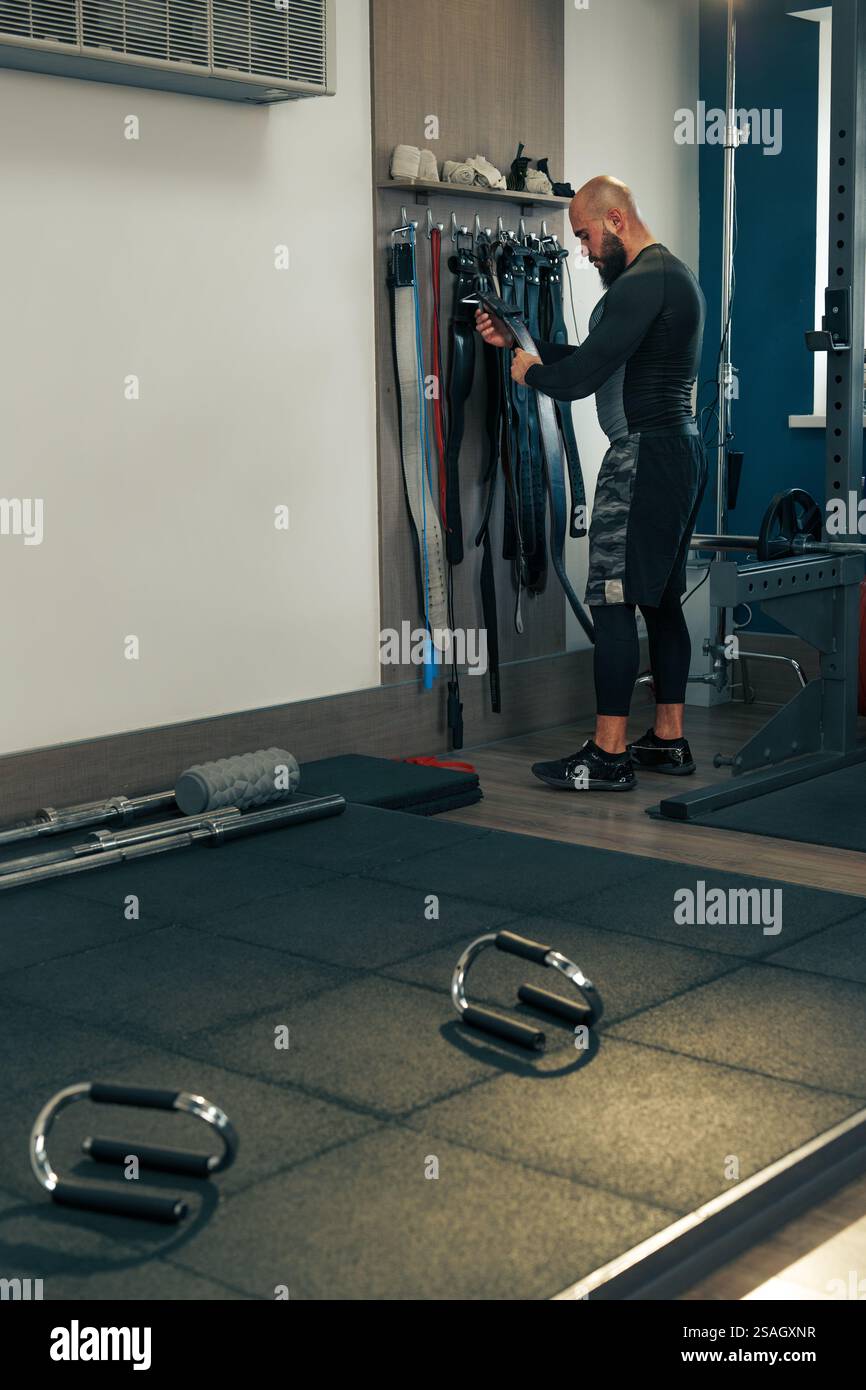 Fitness enthusiast prepares for strength training session at modern gym ...