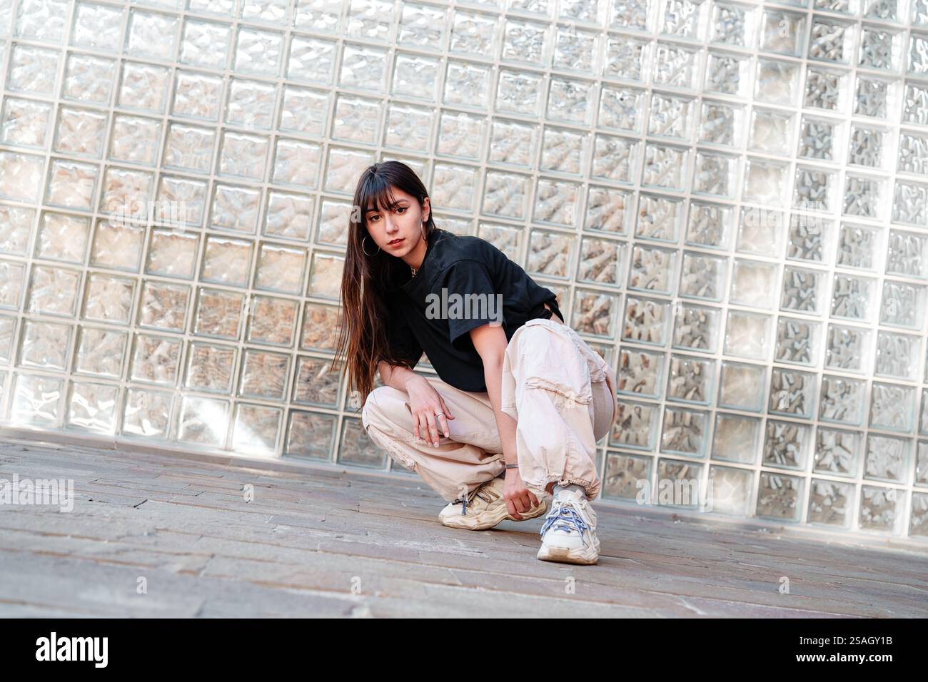 Young dancer poses in urban setting with glass brick wall during ...