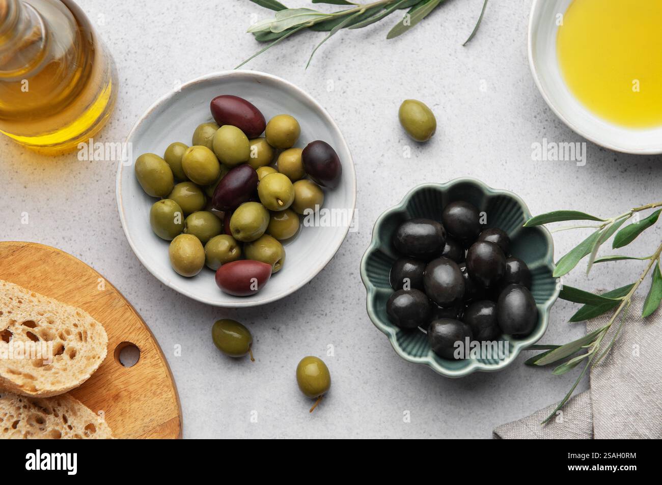 Top view of green and black olives in bowls with olive oil bottle ...