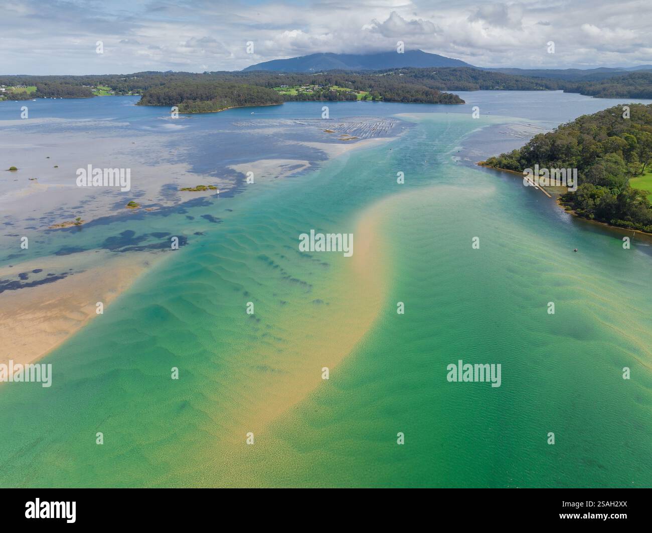 Aerial view of wide inland river with sand bars and a mountain in the ...