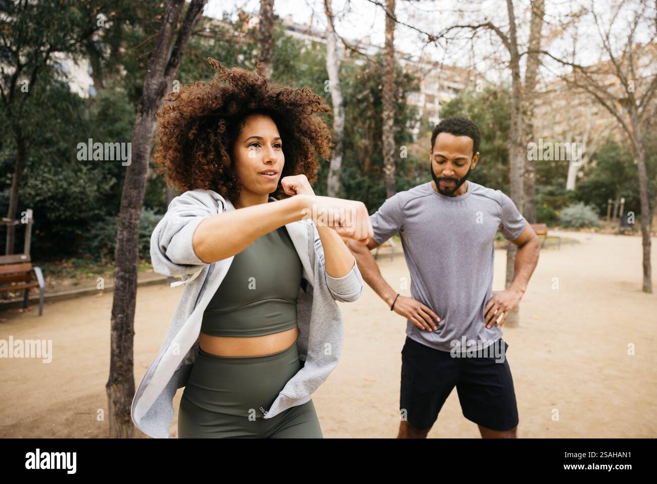 A trainer coaches a student outdoors during a fitness session, focusing ...