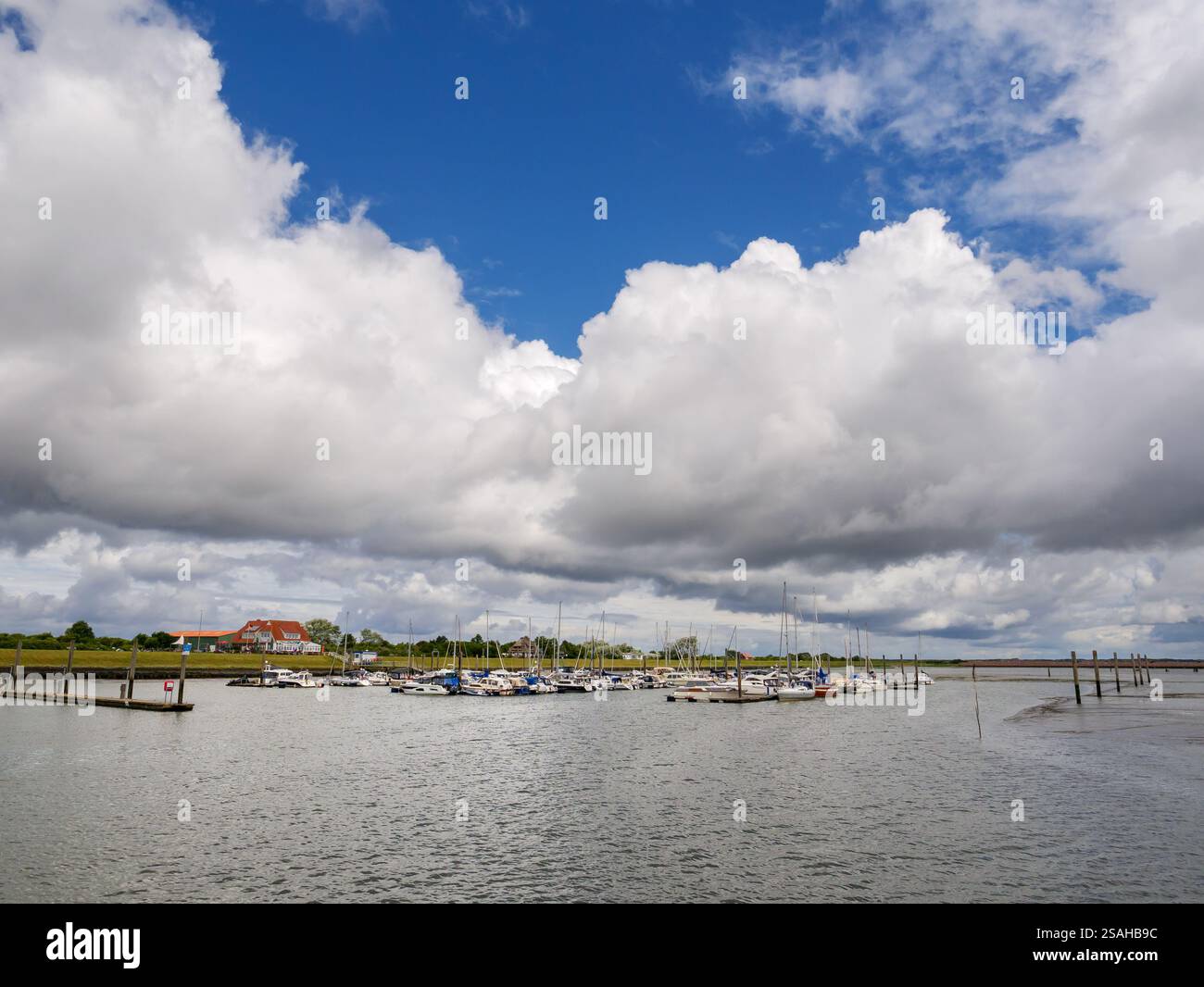 Sailing boats moored in Wadden Sea tidal marina on East Frisian island ...