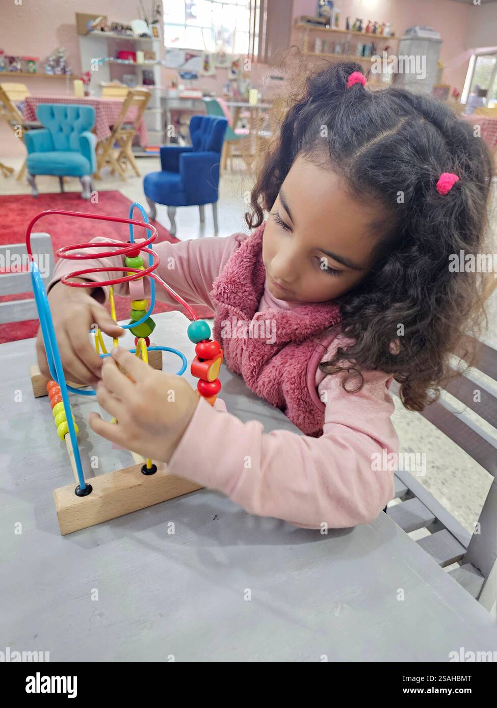 4 year old Latina brunette girl with curly hair plays an educational ...