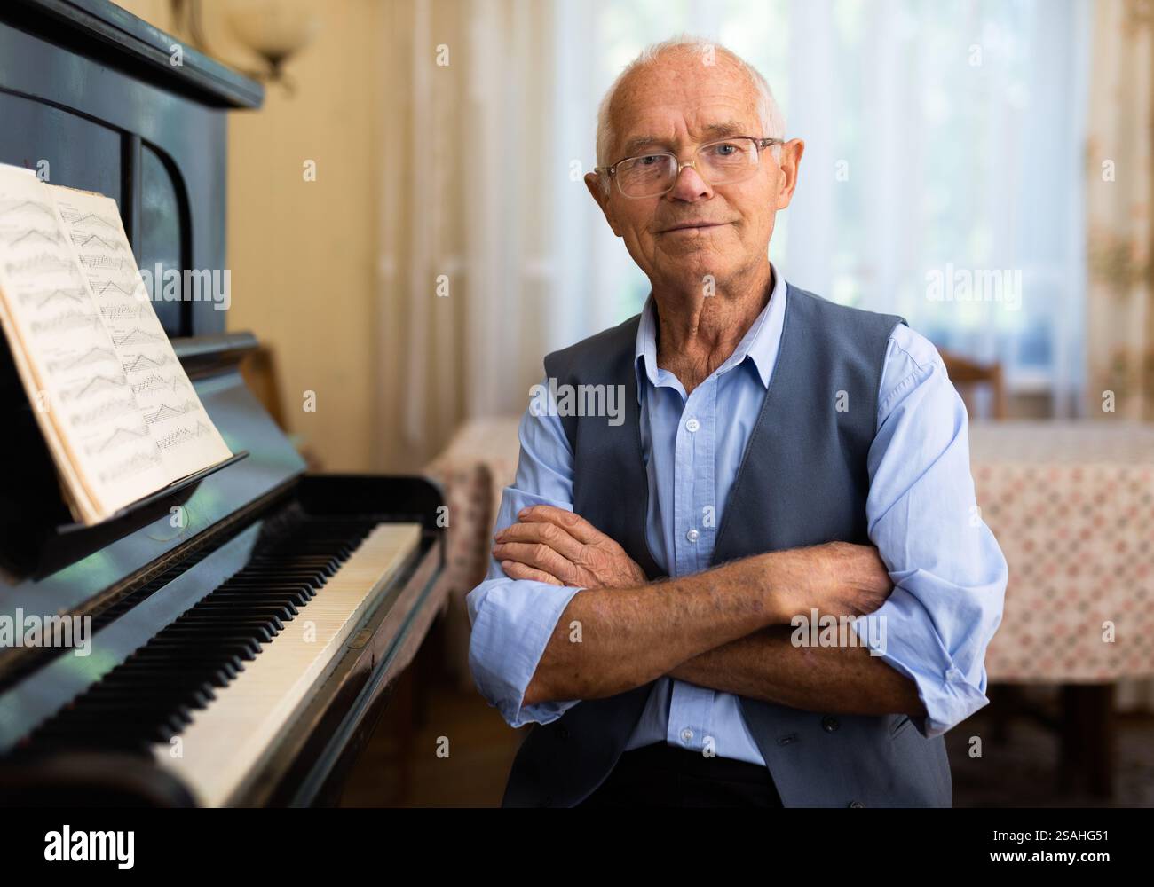 Portrait of positive elderly composer next to piano while composing ...