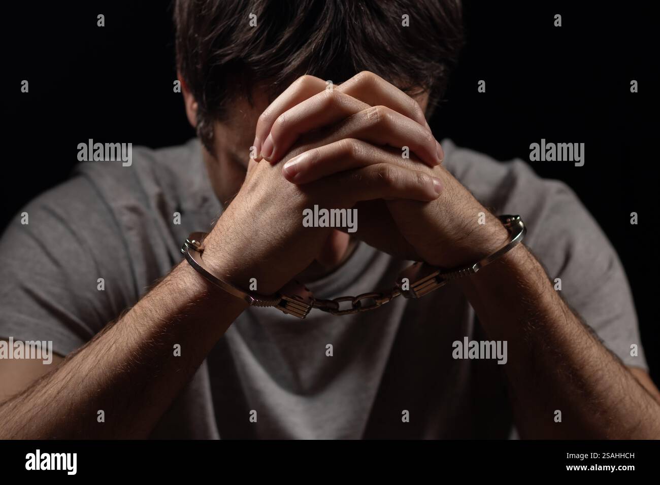 Handcuffed man covering his face with his hands. Arrested and ...