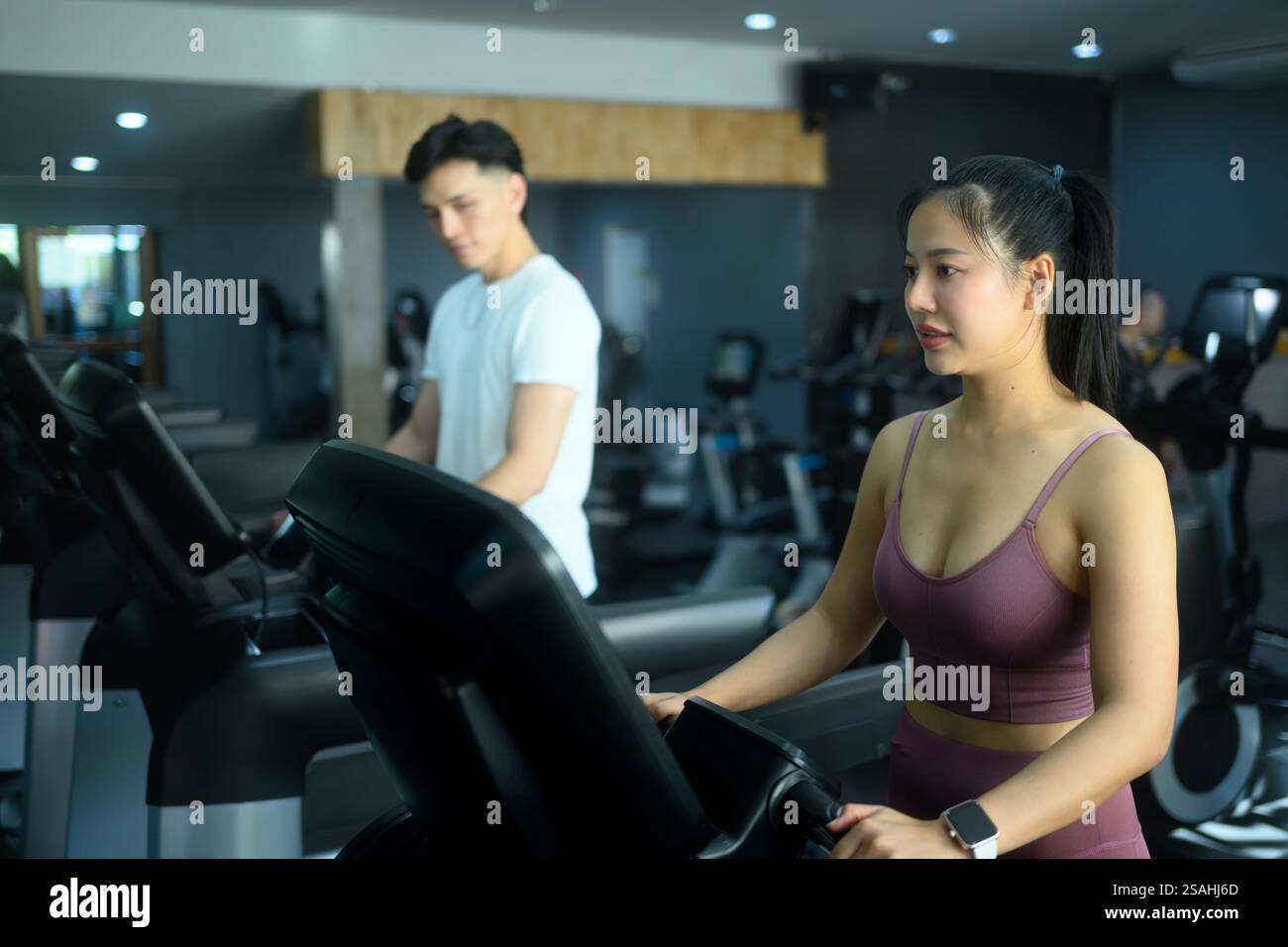 Beautiful woman wearing a smartwatch walking exercising on treadmill in ...