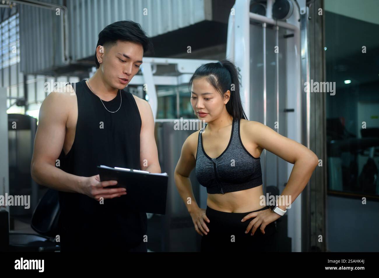 Young sportswoman discussing workout plan and reviewing progress with ...