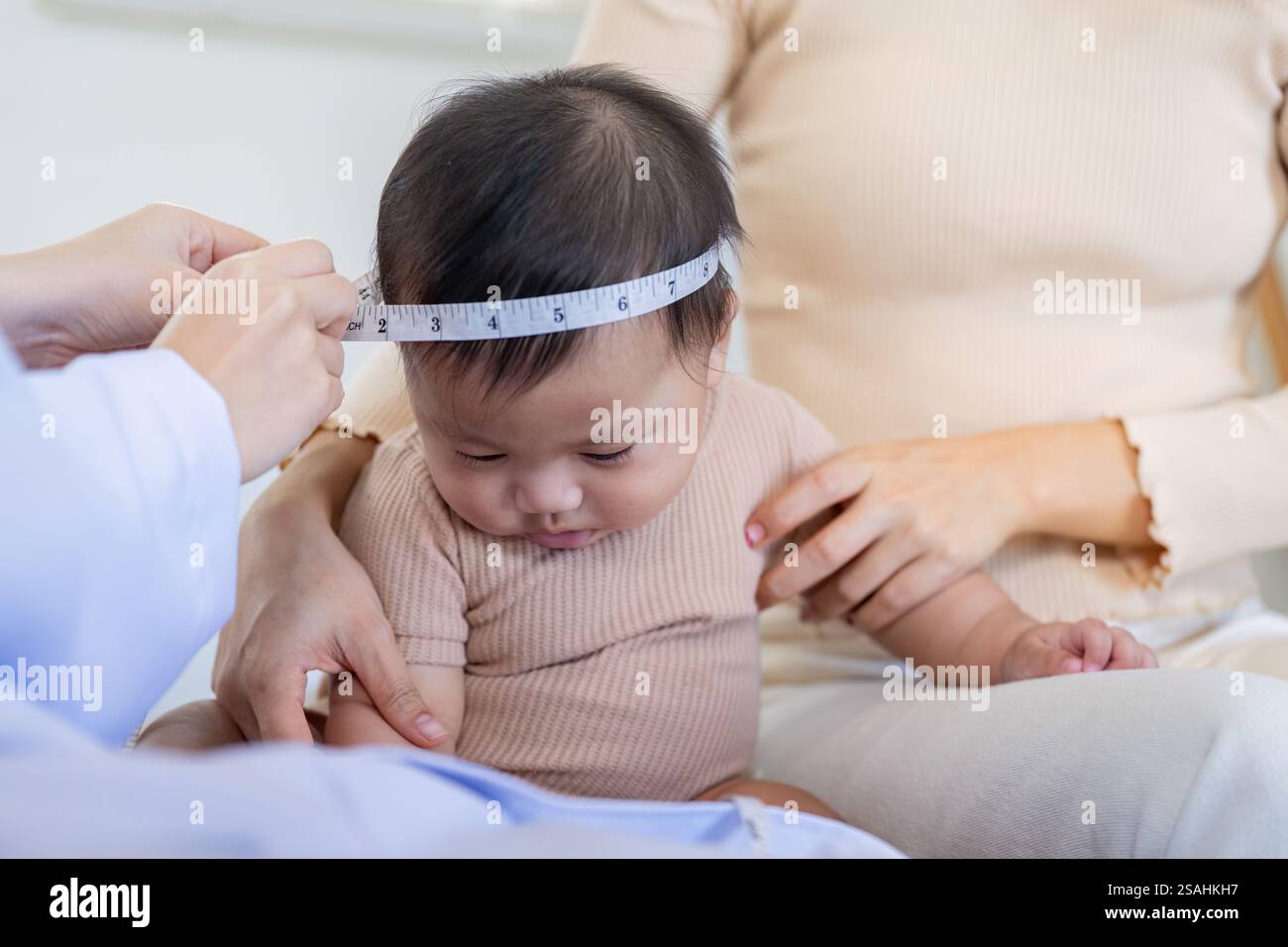 Pediatrician measuring baby's head circumference with tape in clinic ...