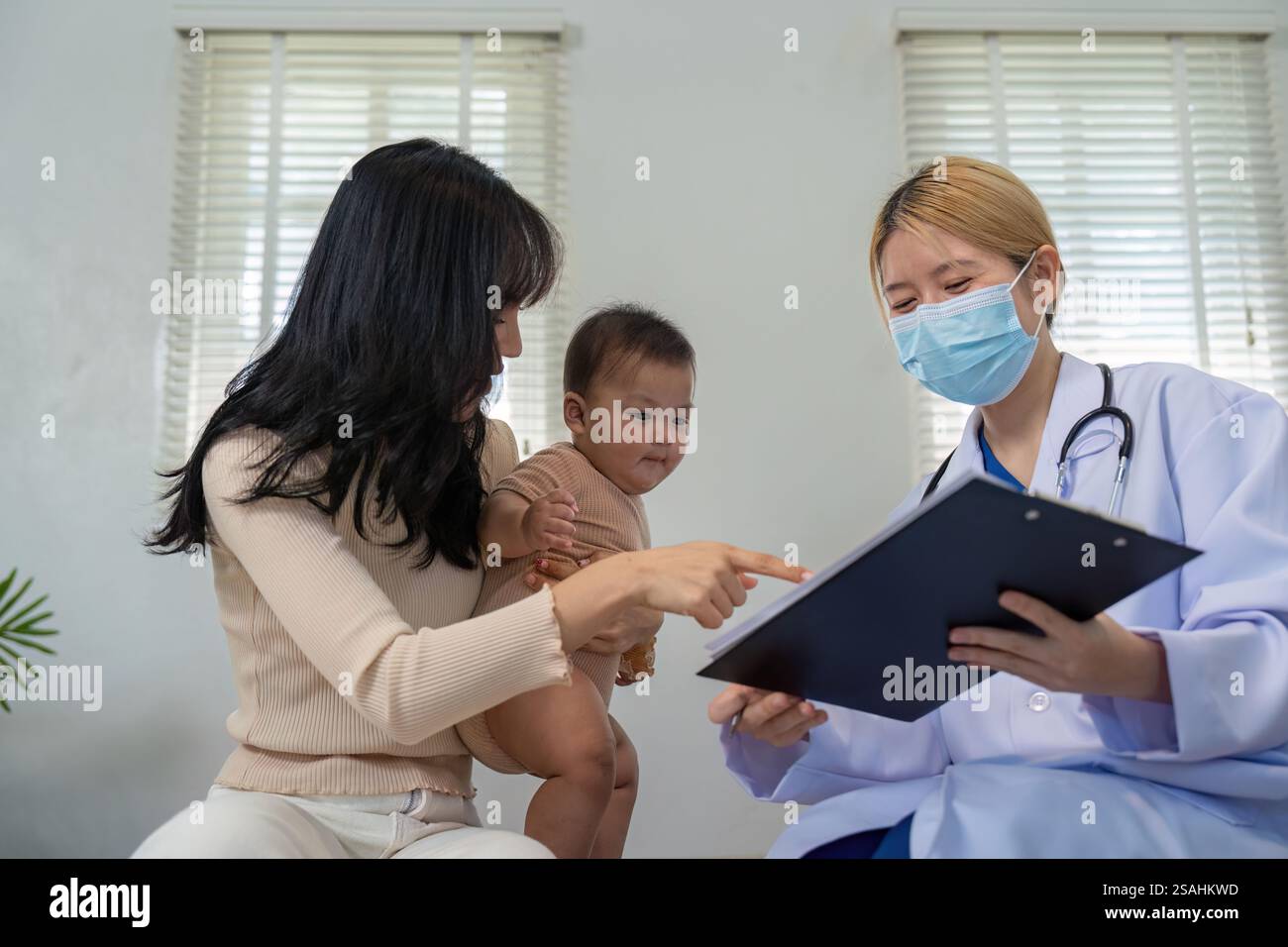 Pediatrician showing medical records to mother and baby during a check ...