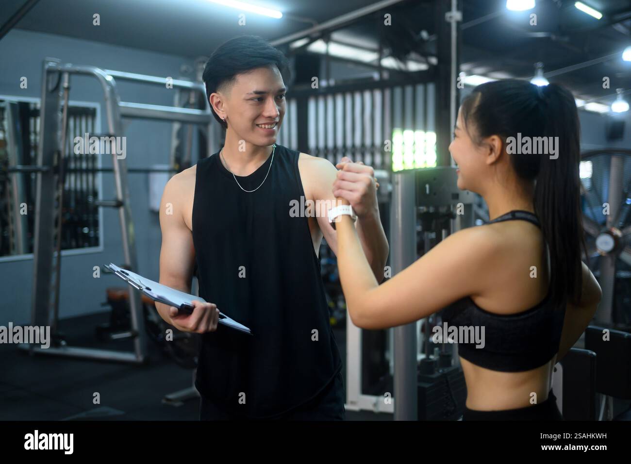 Male personal trainer and his client celebrating fitness progress and ...