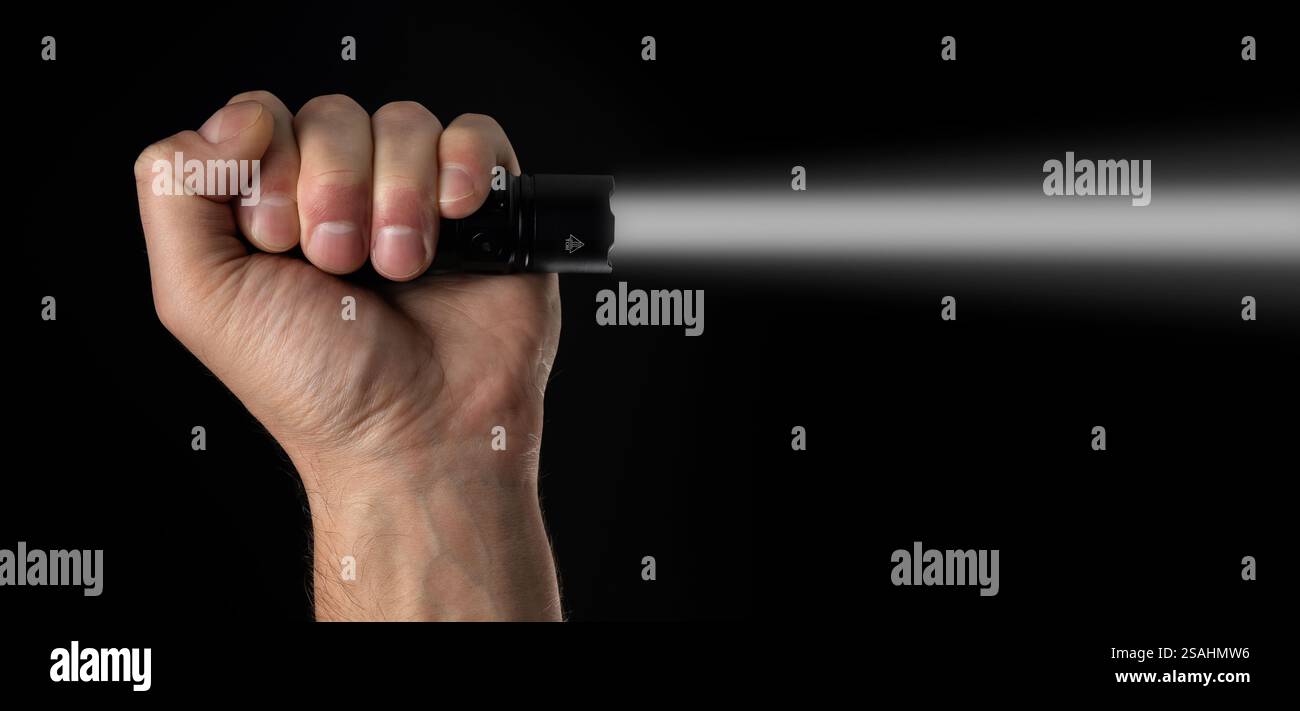 Black flashlight in human hands on a black background, including a ...